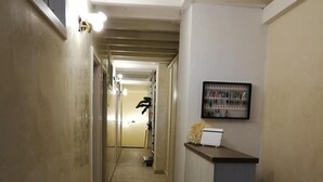 Um corredor estreito com uma mesa de recepção e um quadro na parede.