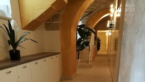 Um corredor com piso ladrilhado, armários brancos e uma planta à esquerda.