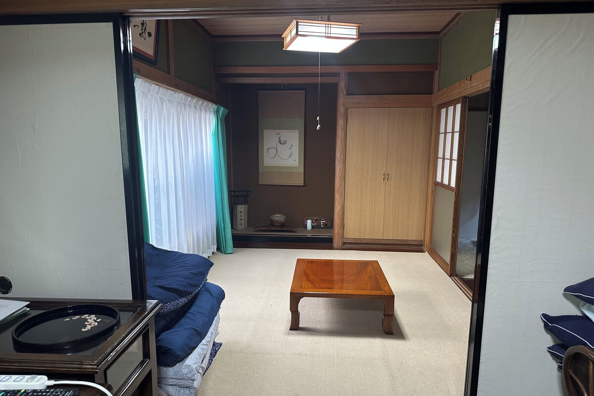 Um quarto em estilo japonês tradicional, com um sofá, uma pequena mesa de madeira e um armário com um rádio.