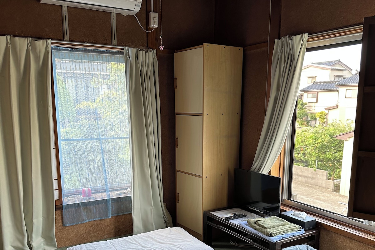 Quarto com cama, televisão, armário e janela com cortinas.