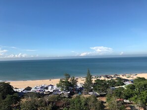 Uma praia com tendas e barcos, árvores e céu claro.