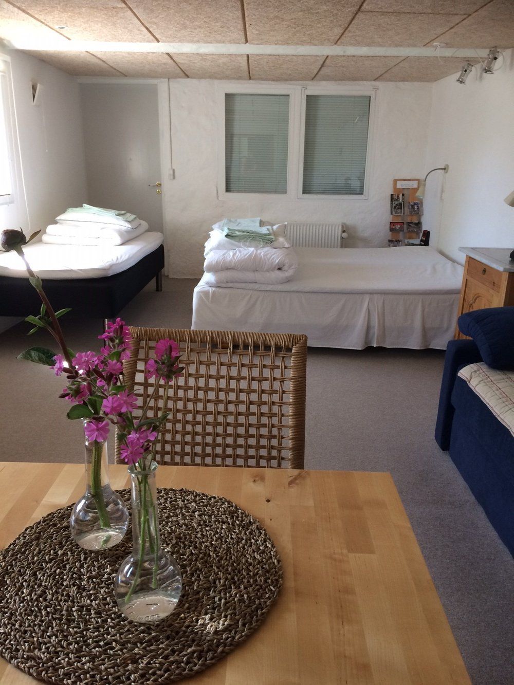 Quarto com duas camas, uma mesa com um vaso de flores e uma cadeira.