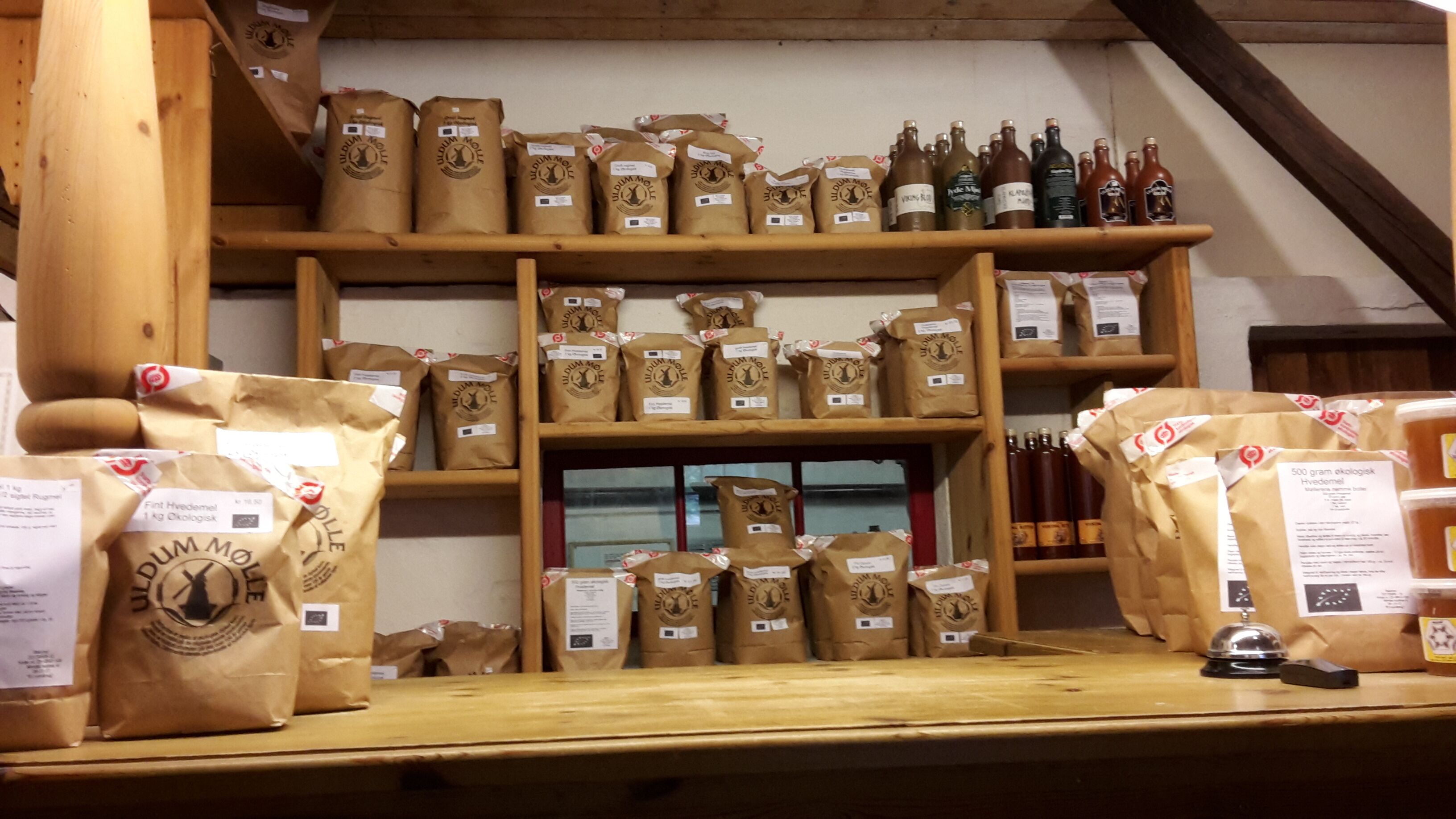 Exposição de sacas e garrafas de café em prateleiras.