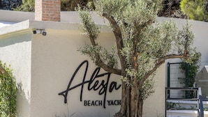 Placa com 'Aleta Beach Yach' e uma árvore na frente.