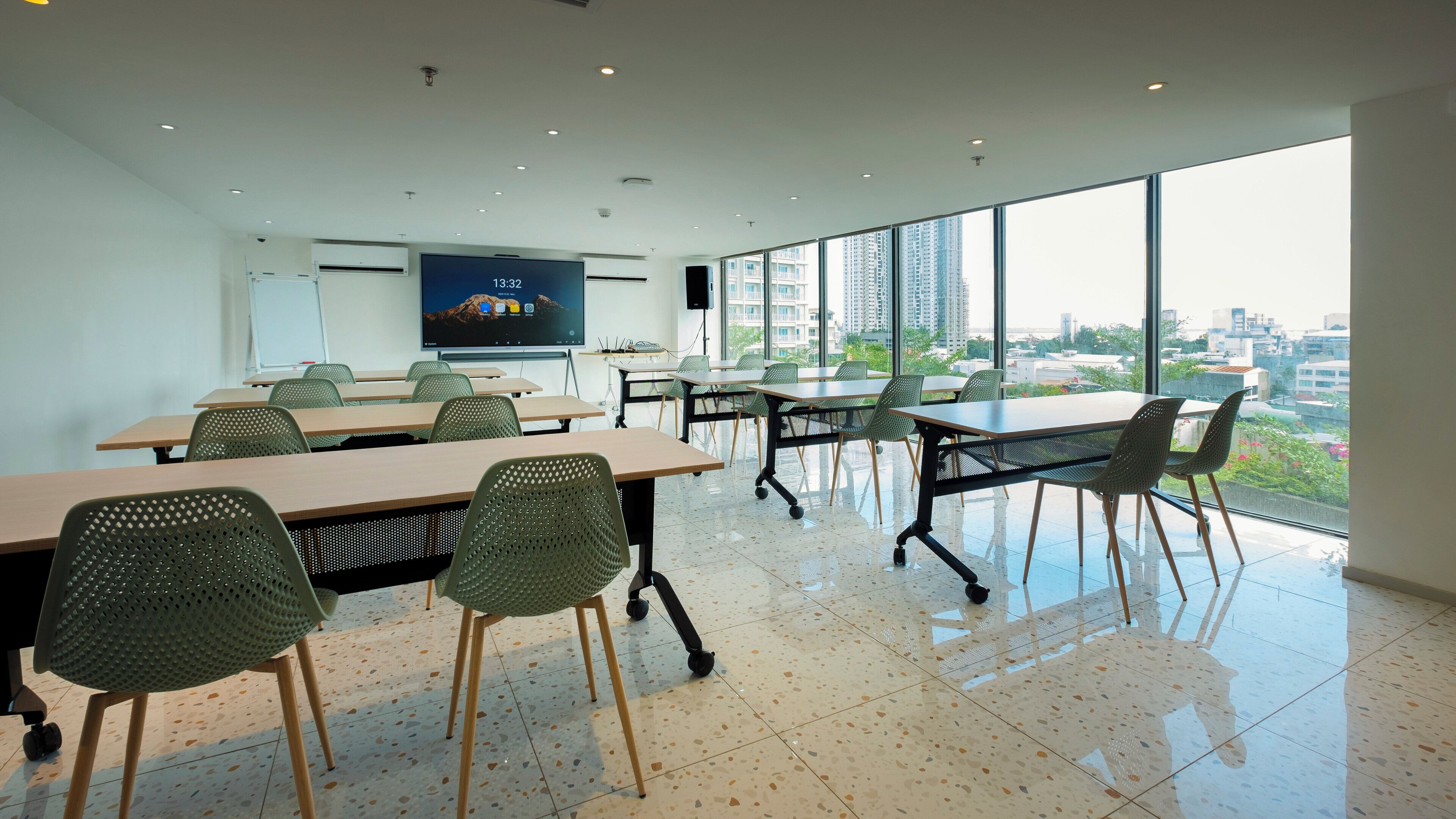 Uma sala de conferência moderna com grandes janelas, um relógio digital e vista para a cidade.