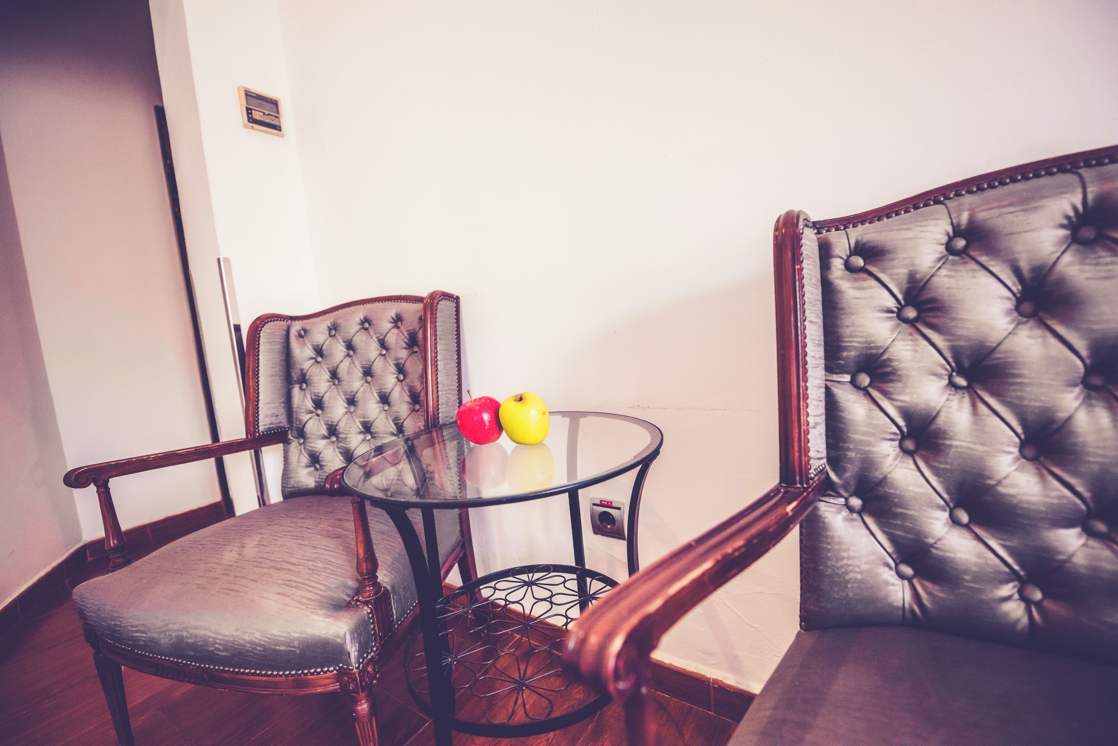 Quarto com duas poltronas de couro, uma mesa de vidro e duas maçãs.
