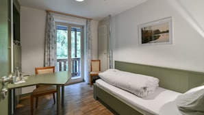 Quarto com cama, mesa, cadeiras, radiador e janela com cortinas.