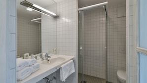 Casa de banho moderna com lavatório duplo, cabine de chuveiro em vidro e sanita.