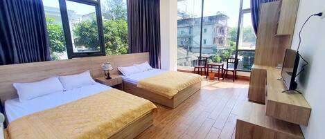Quarto de hotel com duas camas, uma pequena mesa, uma cadeira e uma televisão.