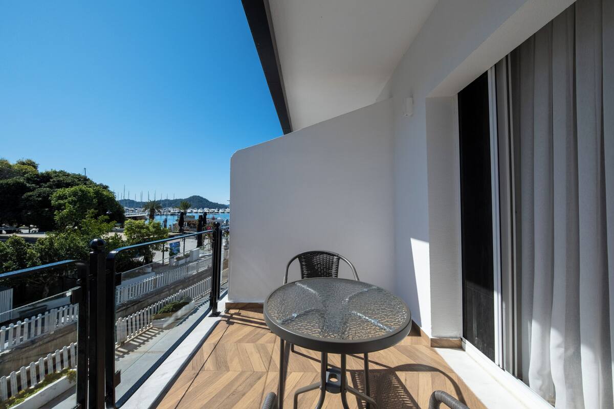 Varanda com mesa e cadeiras, vista da cidade e guarda-corpo.