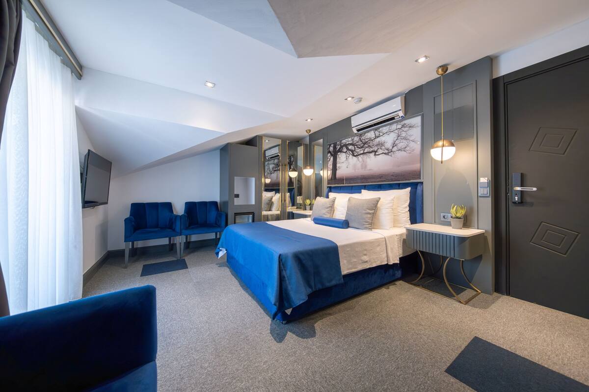 Quarto de hotel moderno com uma cama grande, uma escrivaninha, uma cadeira e uma televisão.