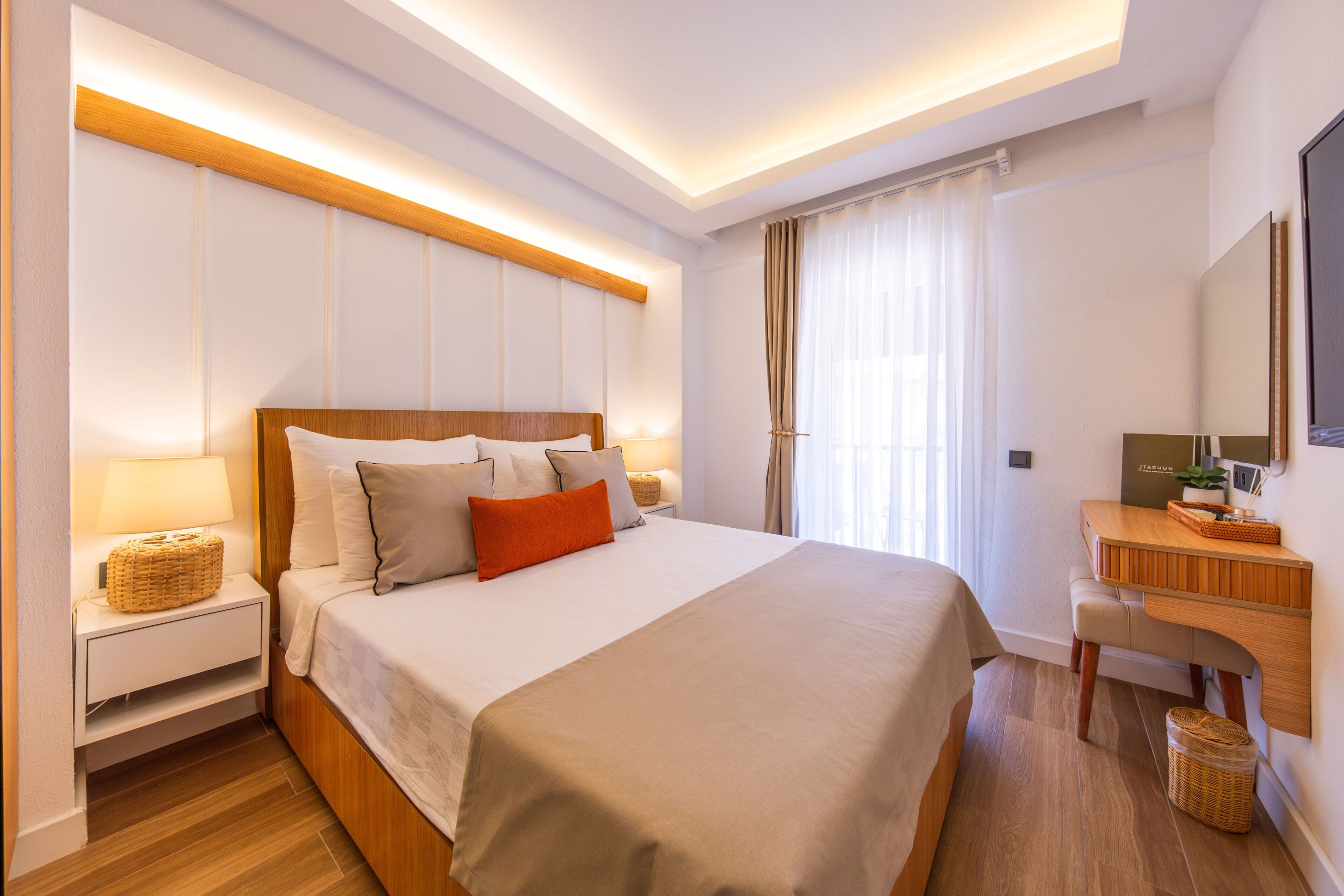 Quarto de hotel moderno com uma cama grande, mesas de cabeceira, escrivaninha e um espelho.