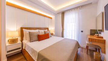 Quarto de hotel moderno com uma cama grande, mesas de cabeceira, escrivaninha e um espelho.
