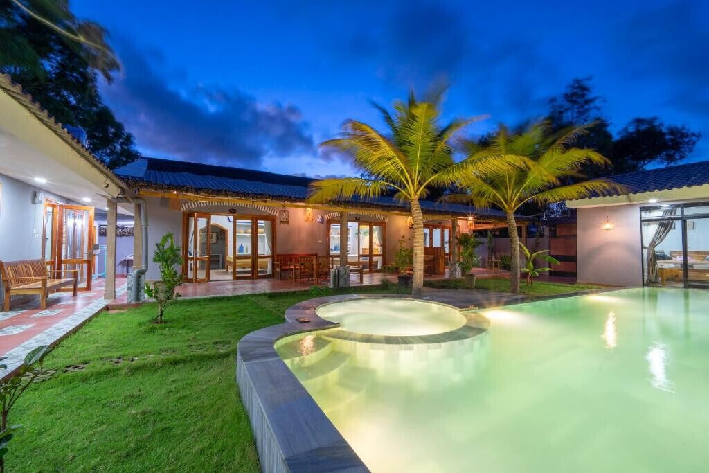 Uma área externa bem iluminada com piscina, palmeiras e um espaço coberto para relaxar.