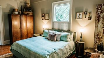 Quarto com cama, guarda-roupa de madeira e janela com persianas.