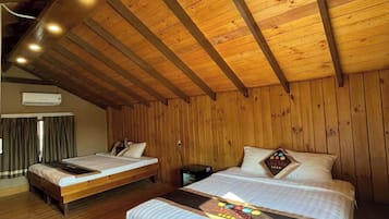 Uma cabana de madeira com duas camas, um ventilador de teto e uma janela com cortinas.