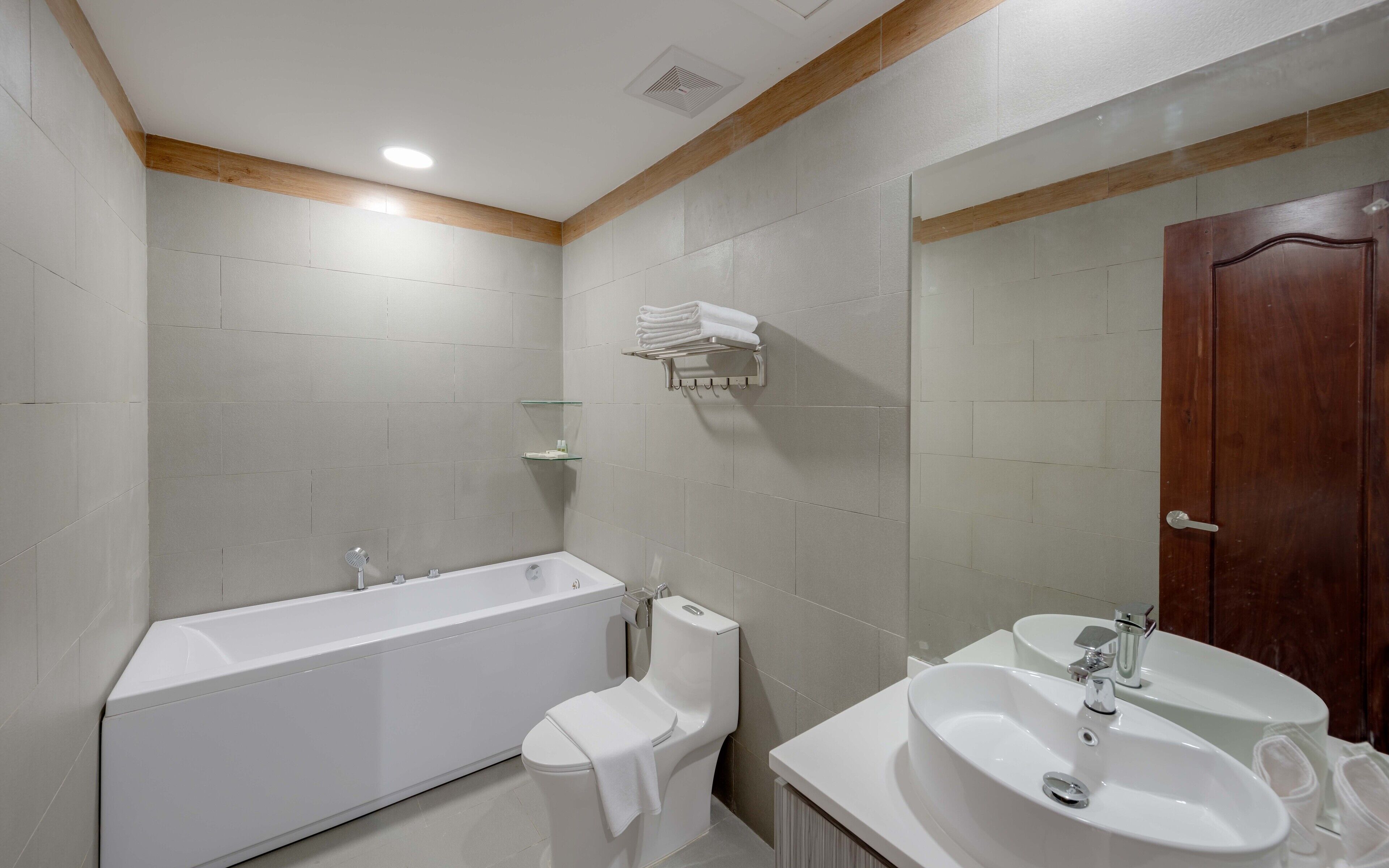 Uma casa de banho moderna com banheira, sanita e duas lavatórios.