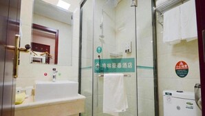 Casa de banho de hotel com cabine de duche em vidro, lavatório e sanita.
