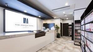 Uma receção com um grande letreiro a dizer "THE MANGA HOTEL" e uma estante cheia de livros de manga.