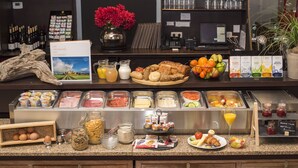 Um buffet de café da manhã com diversos alimentos, bebidas e uma seleção de garrafas de vinho.