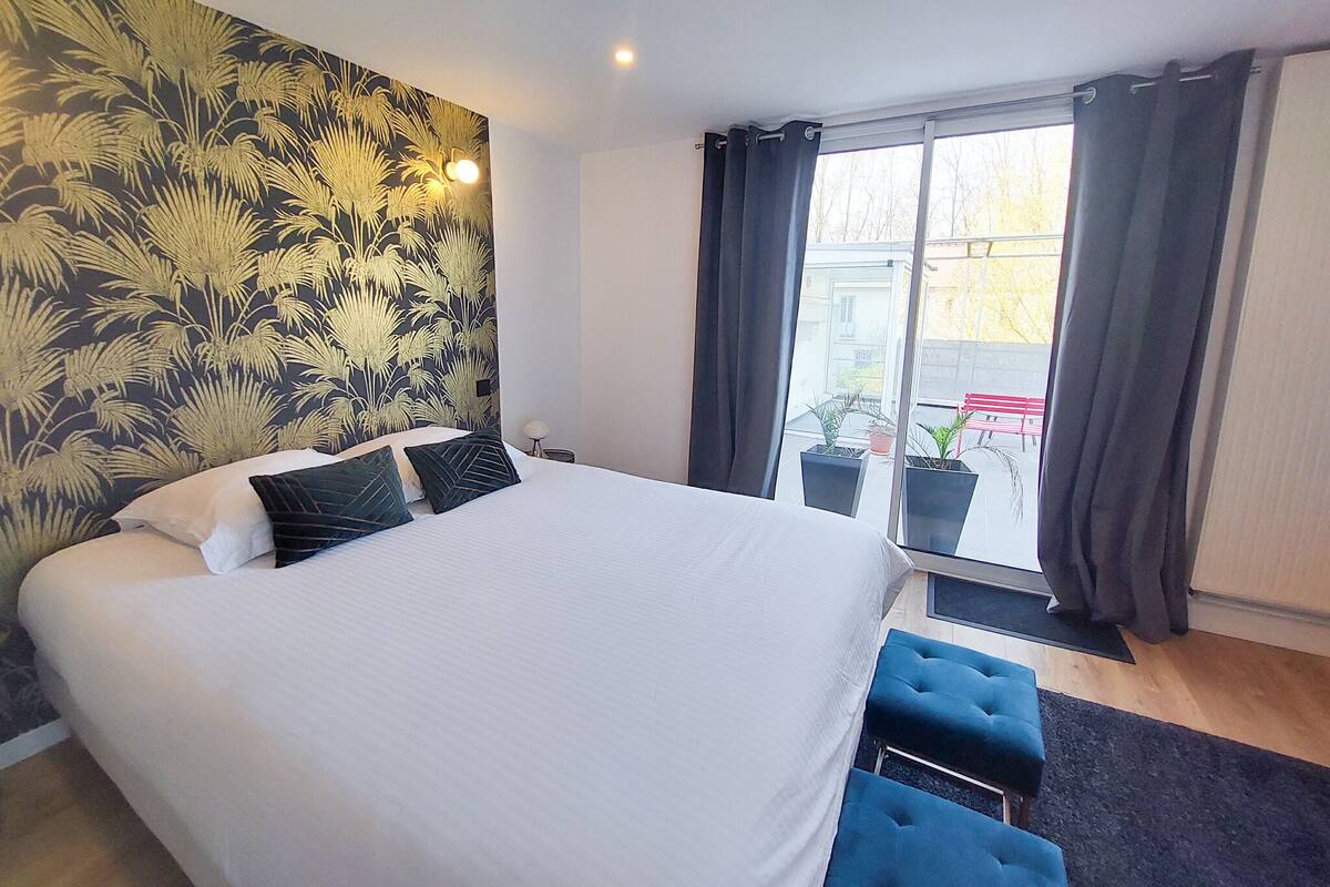 Quarto com cama grande, cortinas escuras e vista para o exterior.
