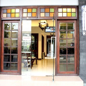 Entrada de hotel com um aviso de 'VACANT', uma escadaria imponente e um interior moderno.