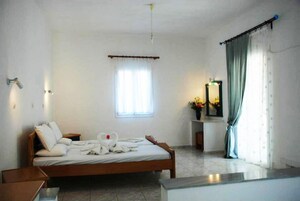 Quarto de hotel com cama, mesa de cabeceira, espelho e janela com cortinas.