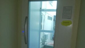 Uma porta com painel de vidro, corrimão e uma placa com texto.