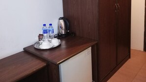 Uma pequena cozinha compacta com geladeira, cafeteira e dispenser de água em bancada de madeira.