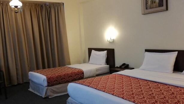 Quarto de hotel com duas camas, um candelabro, um quadro e um telefone na mesinha de cabeceira.