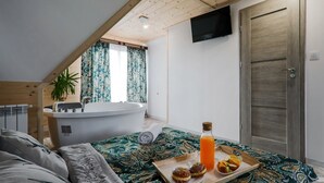 Quarto com cama, mesa de cabeceira, suco de laranja e um tabuleiro com pastelaria.