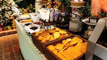Uma mesa de buffet com diversos alimentos e uma árvore de Natal ao fundo.