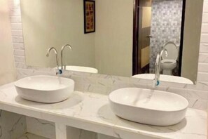 Casa de banho com duas pias brancas e um espelho em cima.