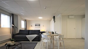 Uma sala de estar moderna com um sofá cinza, uma mesa de jantar com cadeiras e uma pequena mesa de centro.