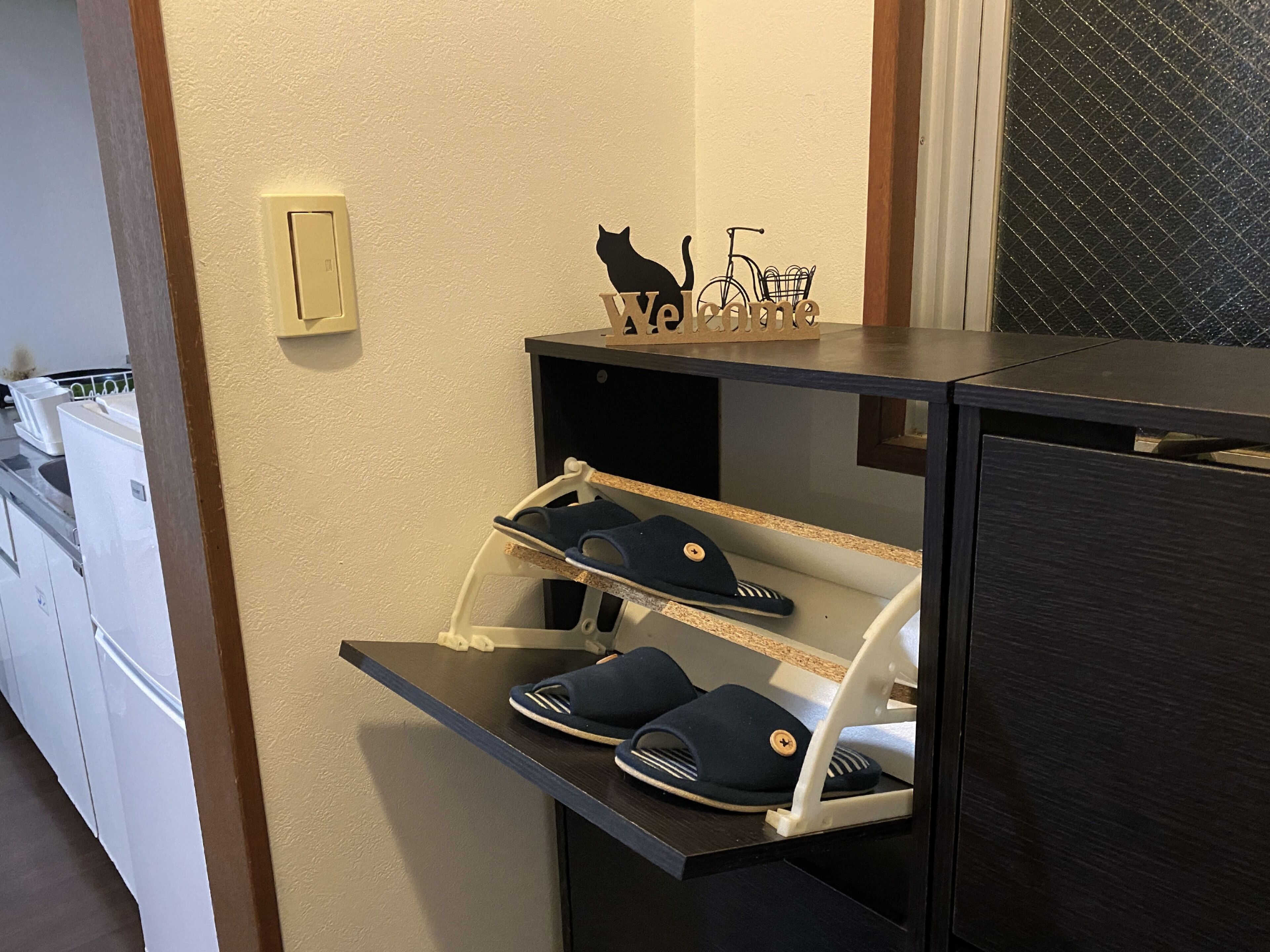 Uma cozinha com eletrodomésticos brancos, uma decoração de gato preto e uma bicicleta em uma prateleira.