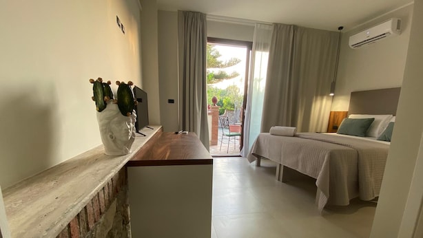 Quarto de hotel com cama, uma pequena mesa e vista para o exterior.