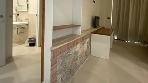 Uma sala de estar moderna com uma parede de destaque em pedra, uma TV de tela plana e uma janela grande com cortinas.