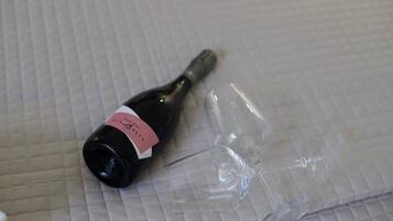 Uma garrafa de vinho e um copo sobre uma superfície acolchoada.