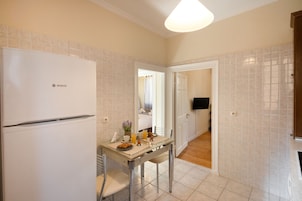 Uma cozinha compacta com geladeira Bosch, uma mesa de jantar com cadeiras e espaço para café da manhã.