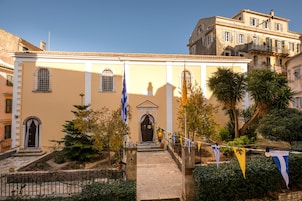 Um edifício com entrada central, uma bandeira e um mastro.