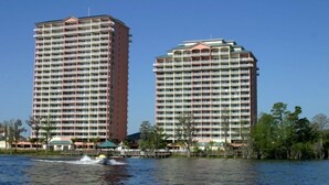 Dois hotéis altos à beira de um corpo de água, com um jet ski em primeiro plano.