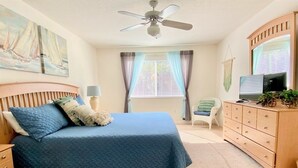 Quarto com cama, cômoda, televisão e ventilador de teto.