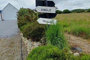 Uma placa de sinalização indicando 'DINGLE' e 'TRALEE' em direções diferentes.