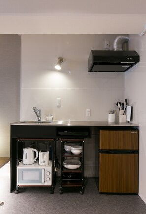 Uma cozinha compacta com pia, micro-ondas, torradeira e um pequeno refrigerador.