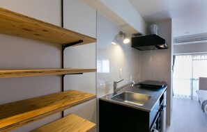 Uma cozinha moderna com prateleiras de madeira, pia de aço inoxidável e coifa preta.