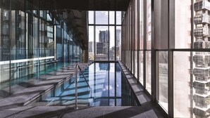 Uma área de piscina interna moderna, com paredes de vidro e vista clara para a paisagem urbana.