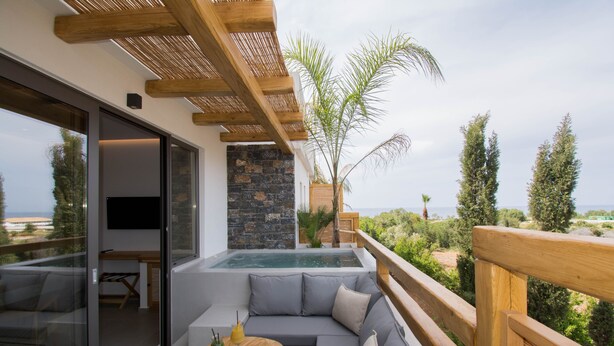 Uma área externa moderna com hidromassagem integrada, deck de madeira e vista para o oceano.