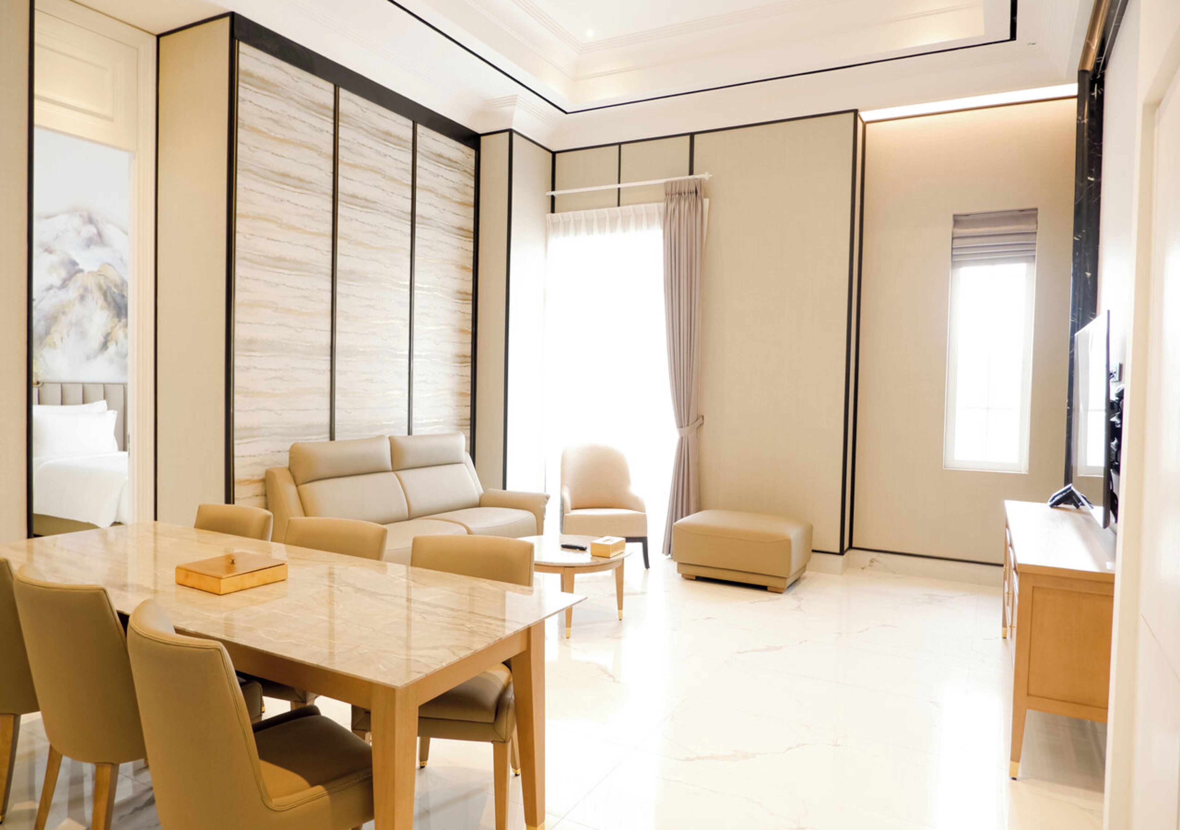 Uma sala de estar moderna com uma mesa de centro de mármore, sofás bege e uma área de jantar com mesa e cadeiras de madeira.