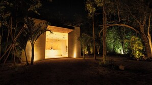 Um edifício moderno com entrada aberta, rodeado por árvores.