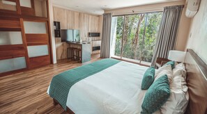 Quarto de hotel com uma cama grande, uma escrivaninha com cadeira, televisão e janela com cortinas.